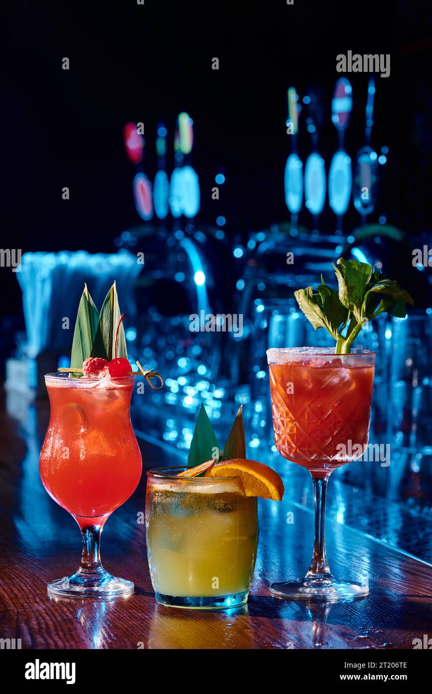three different refreshing cocktails on bar counter with bar on ...