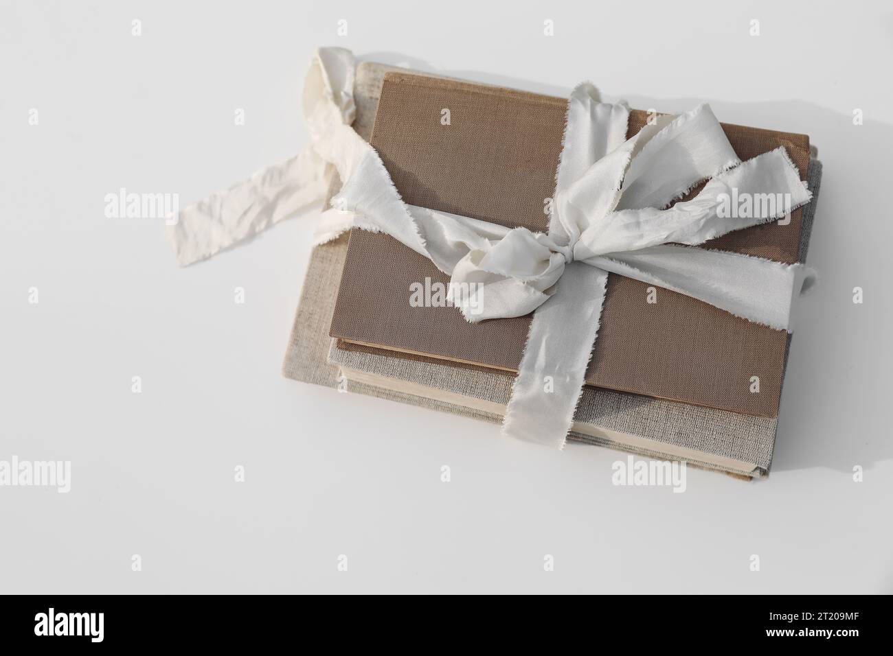 Stack of three old, vintage books tied up with beige ribbon with linen ...