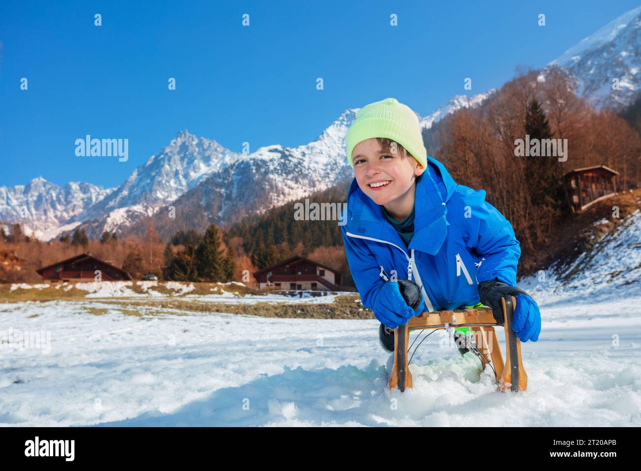 Cute smiling boy in the winter outfit lay on wooden sledge Stock Photo ...