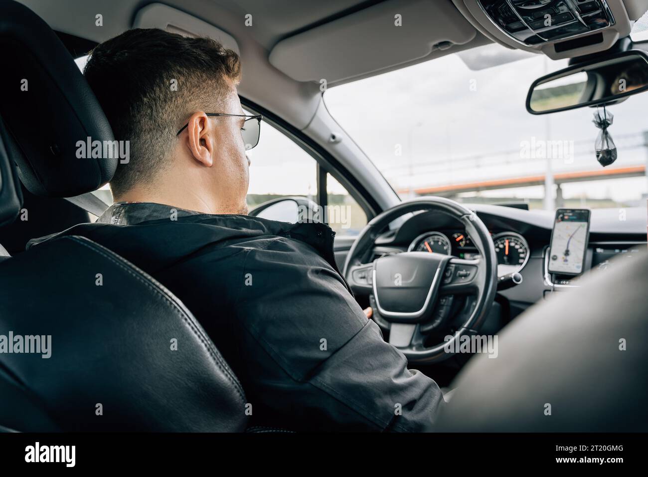 A man drives a car using a navigation application installed on a ...