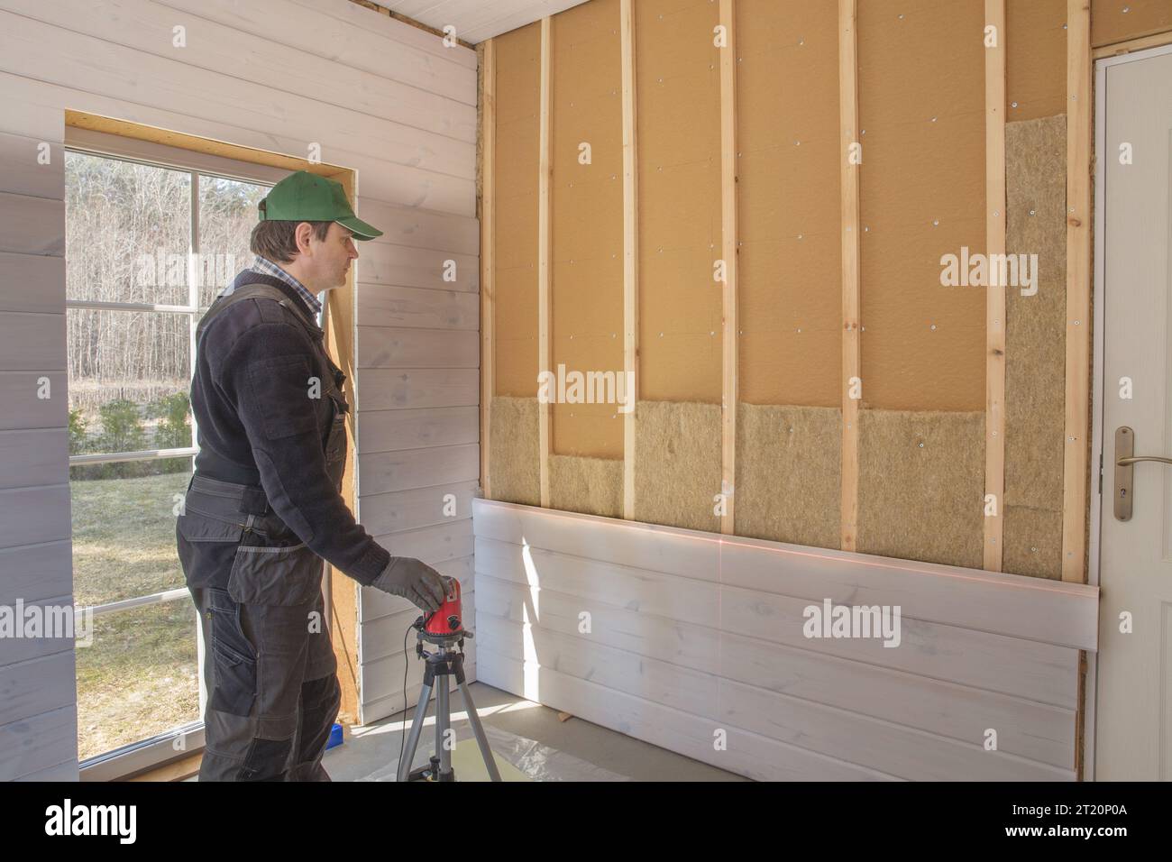 The worker makes finishing works of walls with a white wooden board ...