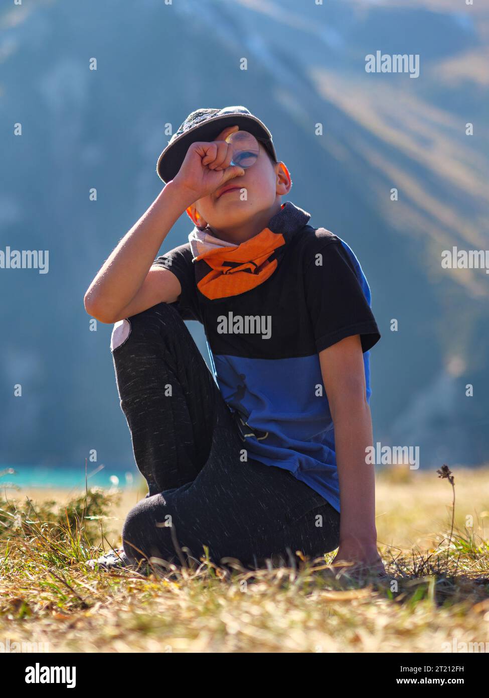 A boy plays with a magnifying glass. A child plays outdoors in the ...