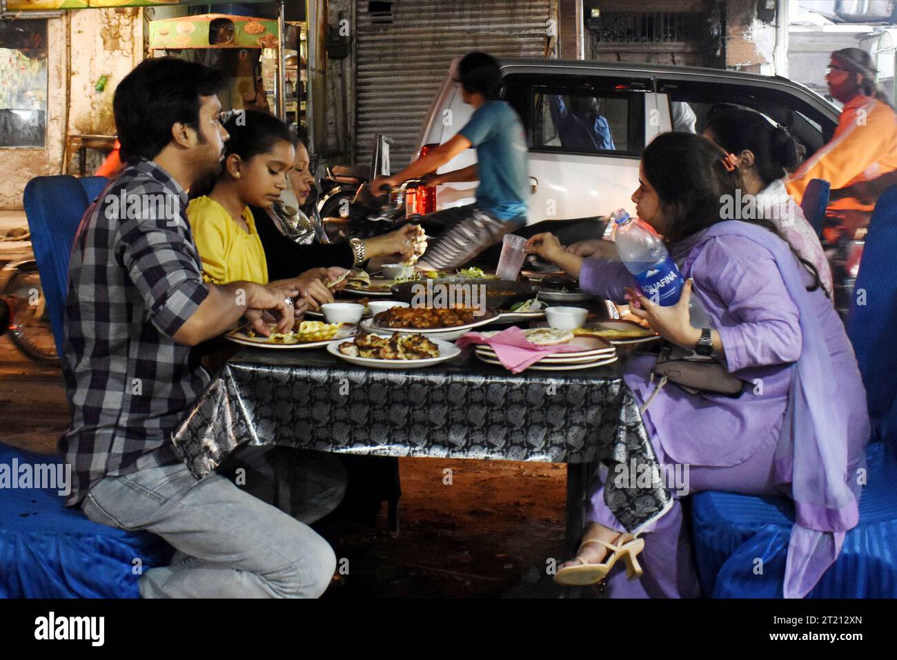 Lahore, Pakistan. 15th Oct, 2023. People enjoy food by the street in ...