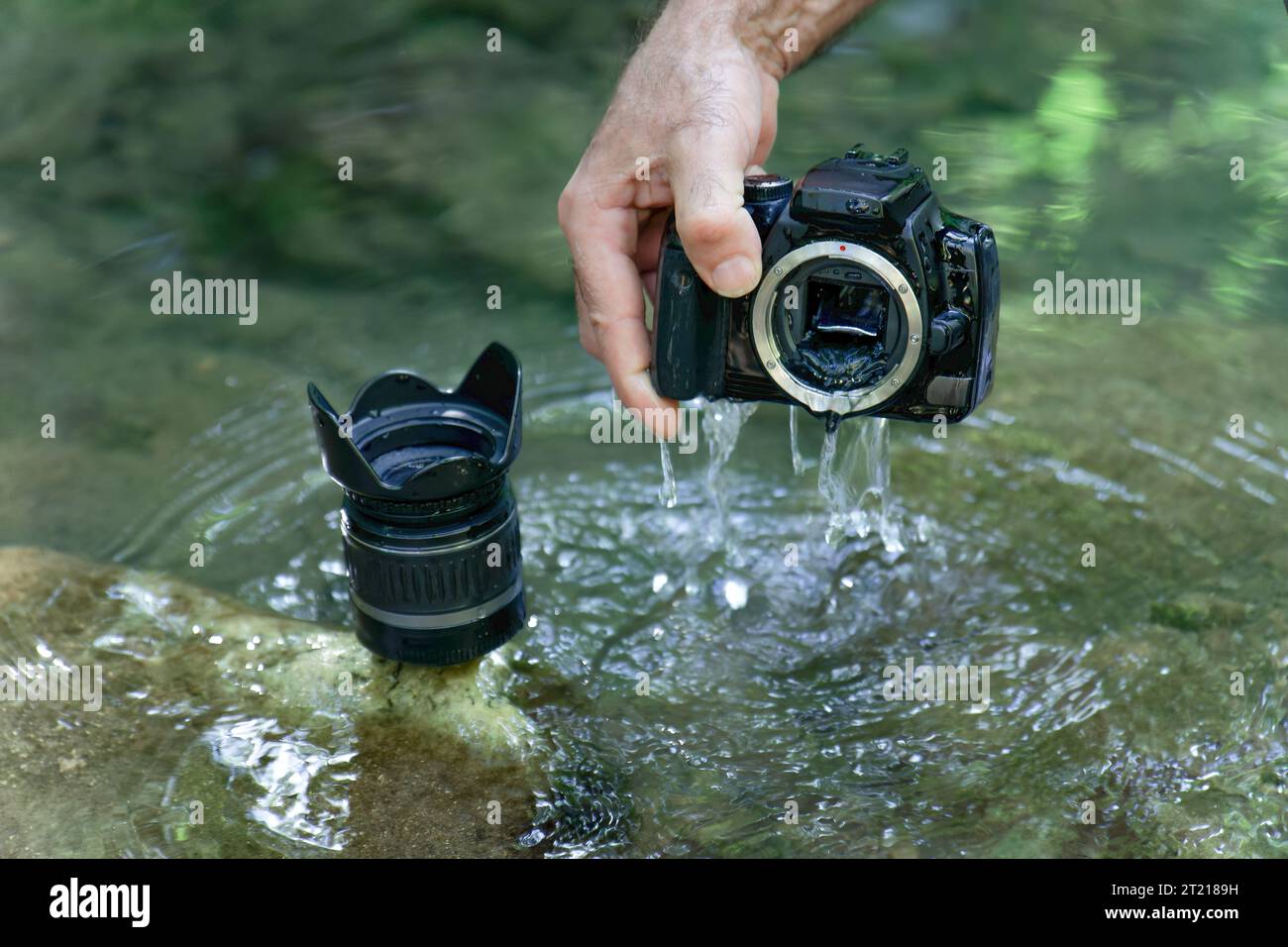 man pulls his digital camera out of the river that has accidentally ...