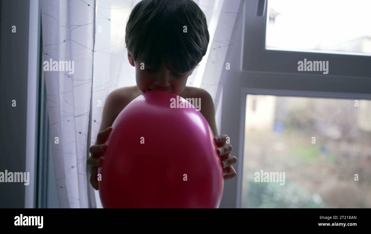 One adorable child deflating balloon with teeth. Little boy biting ...