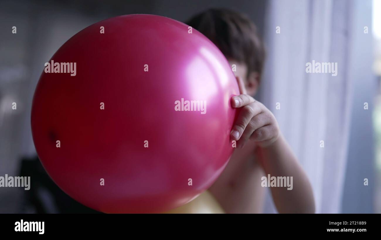 One fun child blowing up balloon with mouth. Happy small boy biting ...