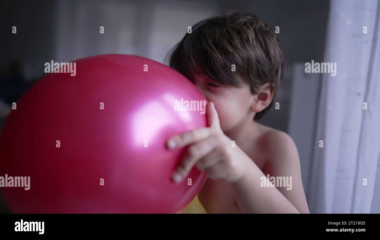 One fun child blowing up balloon with mouth. Happy small boy biting ...