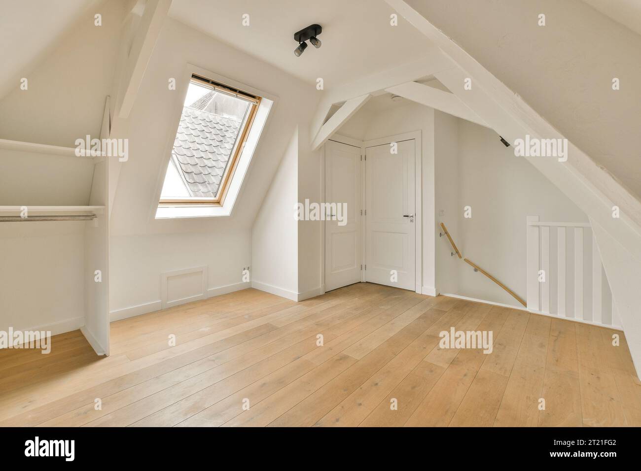an empty room with wood flooring and skylights on the top of the attic ...