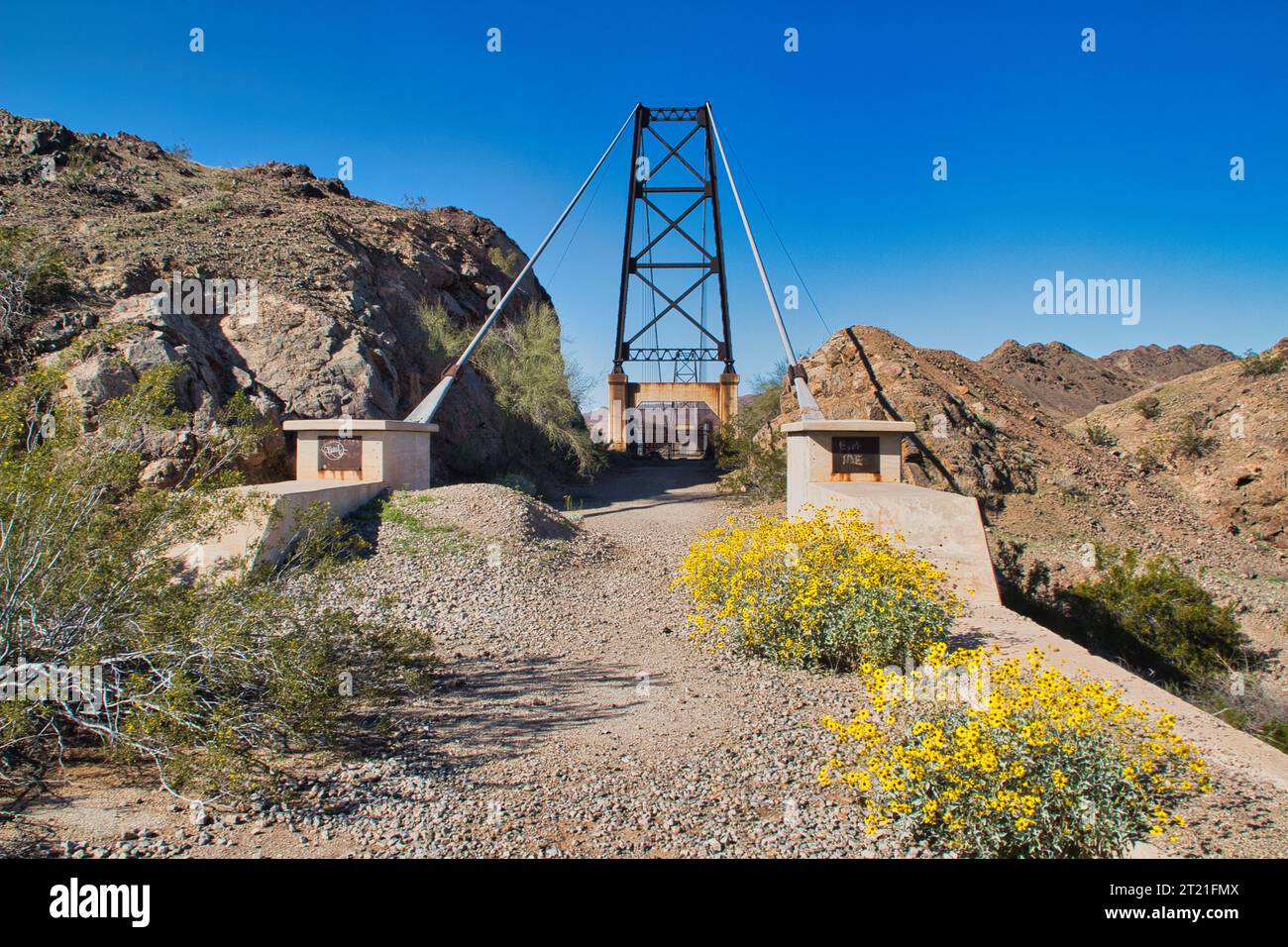 A metal bridge spanning a vast desert plain and rocky canyon walls ...