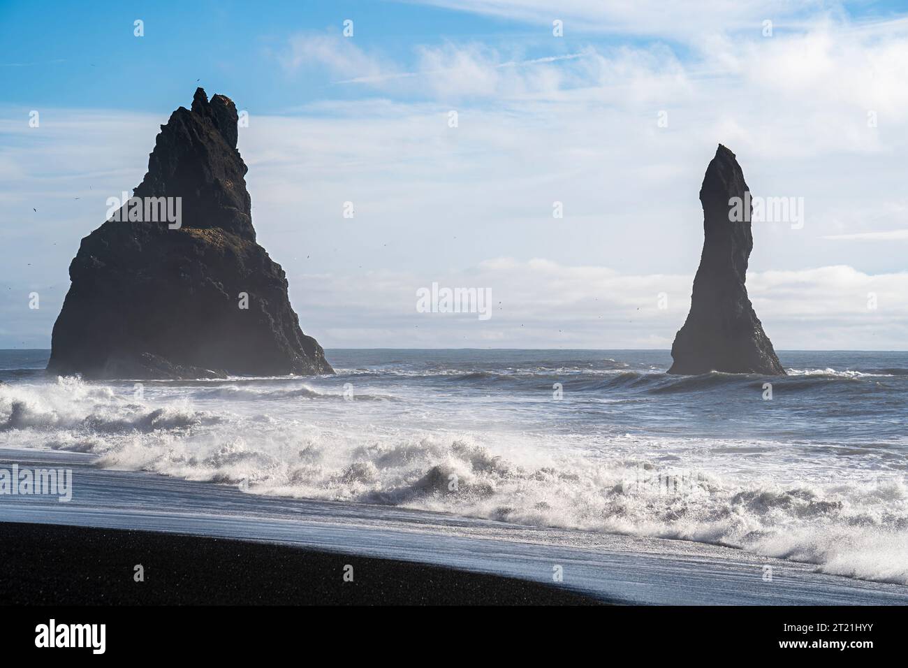 An idyllic black sand beach in Iceland with two prominent basalt towers ...