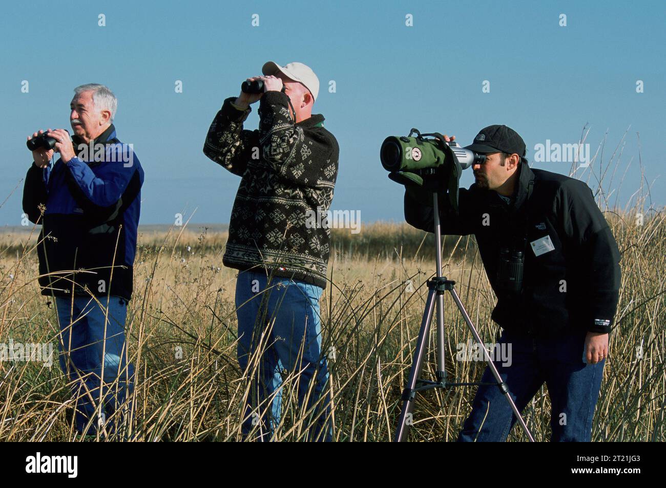 A group of men stand birdwatching at the Long Lake National Wildlife ...