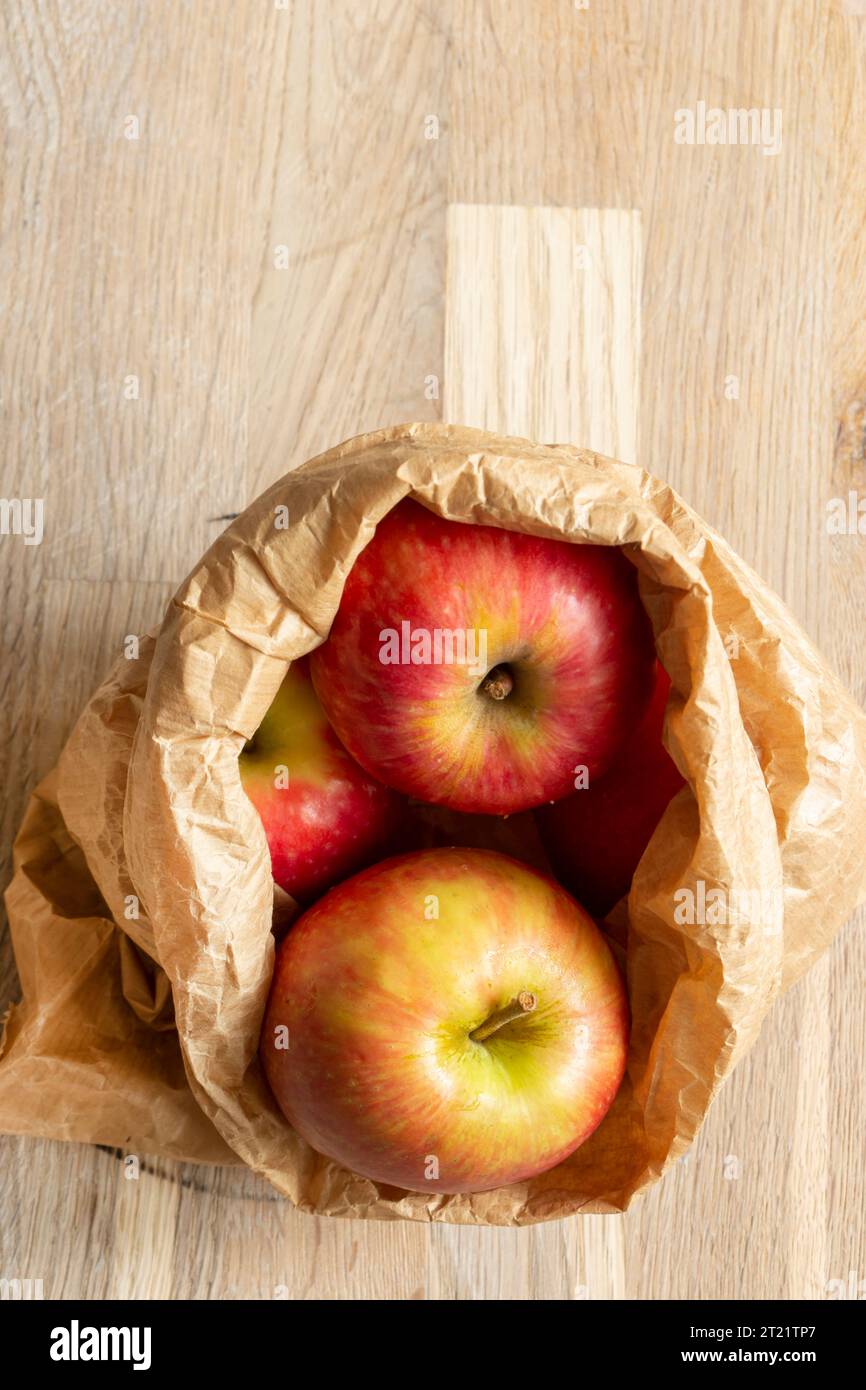 Apples, Pink Lady variety, in a brown paper bag on a wood background ...