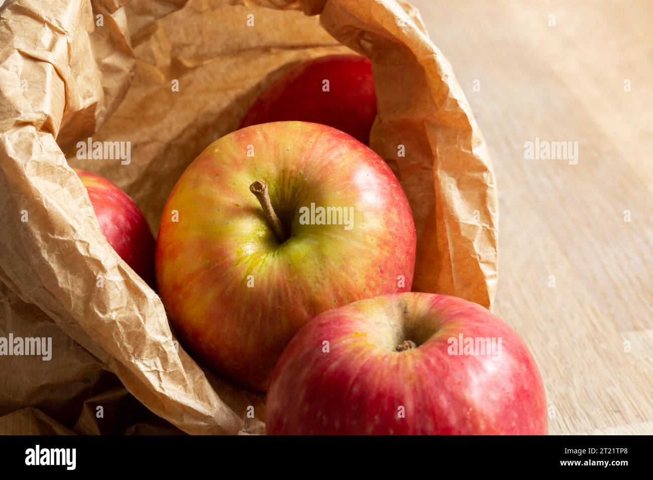 Apples, Pink Lady variety, in a brown paper bag on a wood background ...
