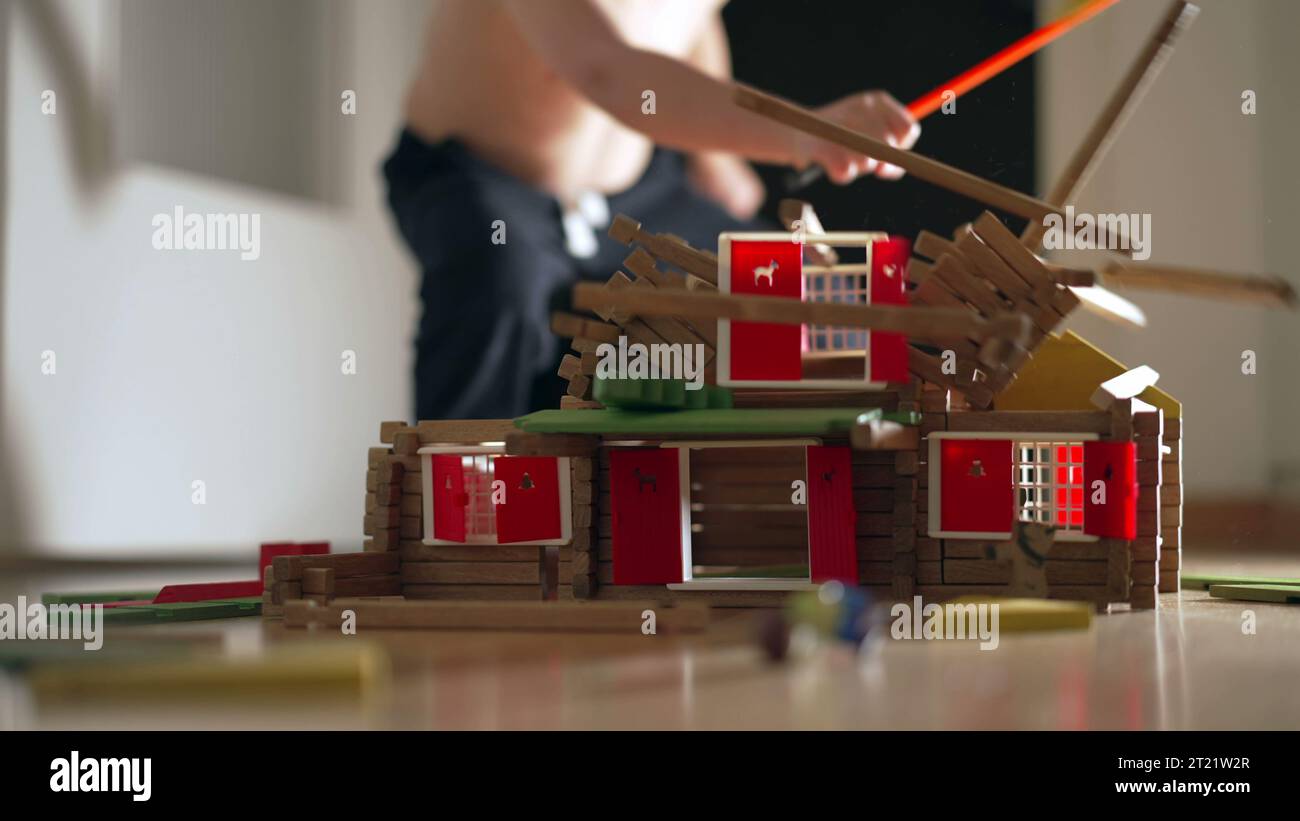 Child destroying house construction miniature. Kid kicking model wood ...