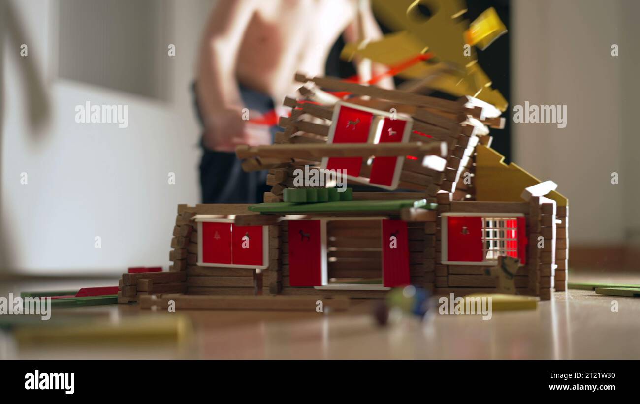 Child destroying house construction miniature. Kid kicking model wood ...