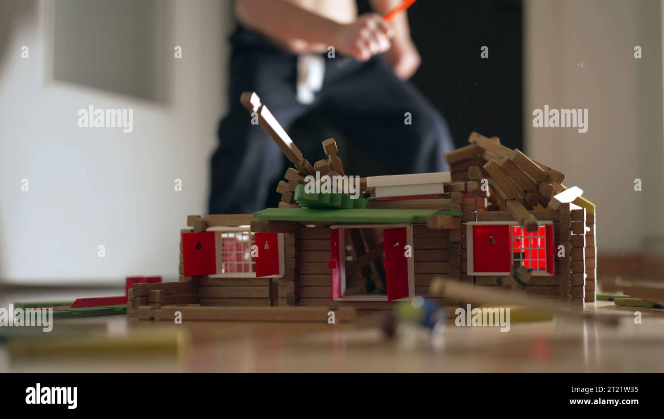 Child destroying house construction miniature. Kid kicking model wood ...