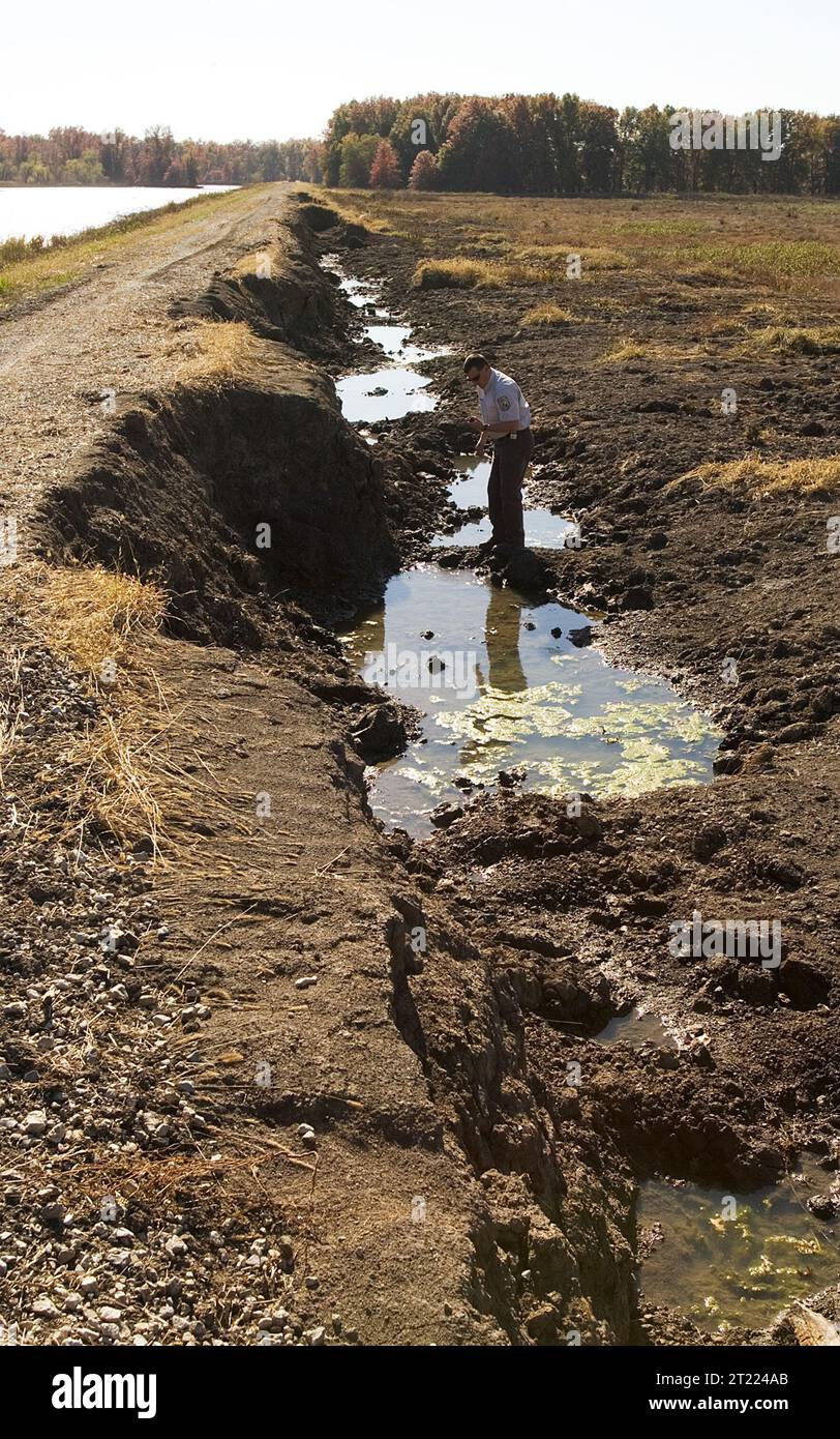 One U.S. Fish and Wildlife Service employee standing below earthen dam ...