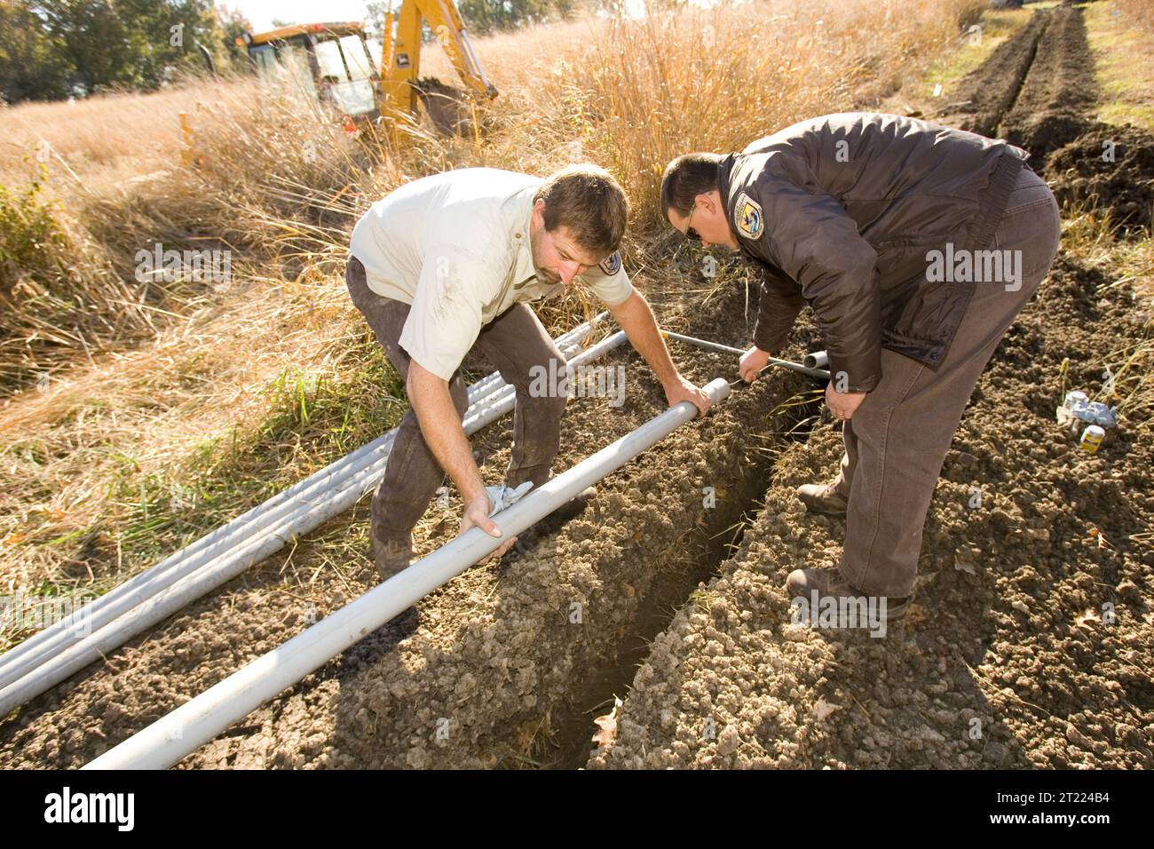 Two U.S. Fish and Wildlife Service employees laying pipe. Subjects ...