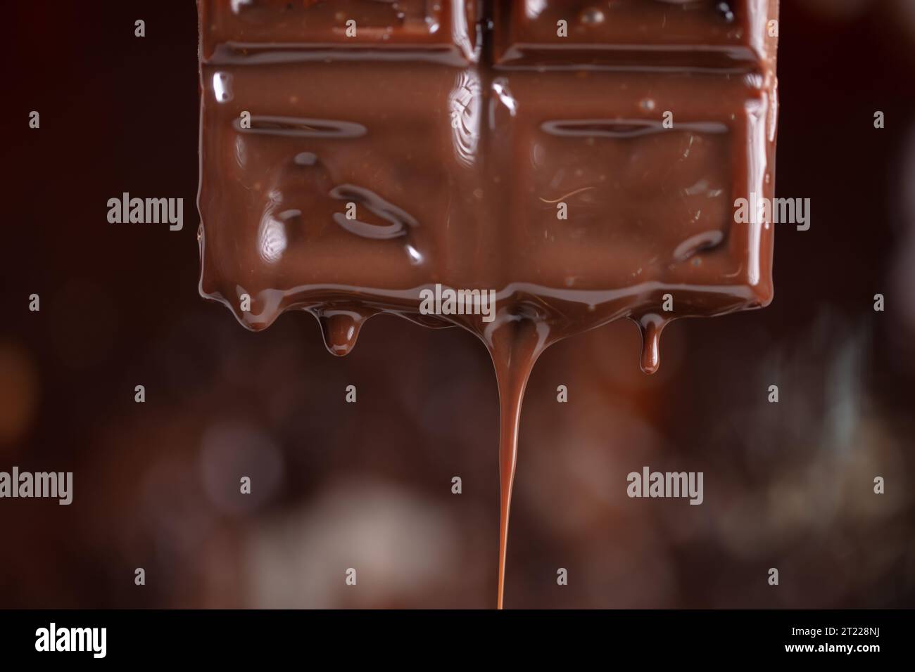 Melted chocolate drips down on a brown background Stock Photo - Alamy