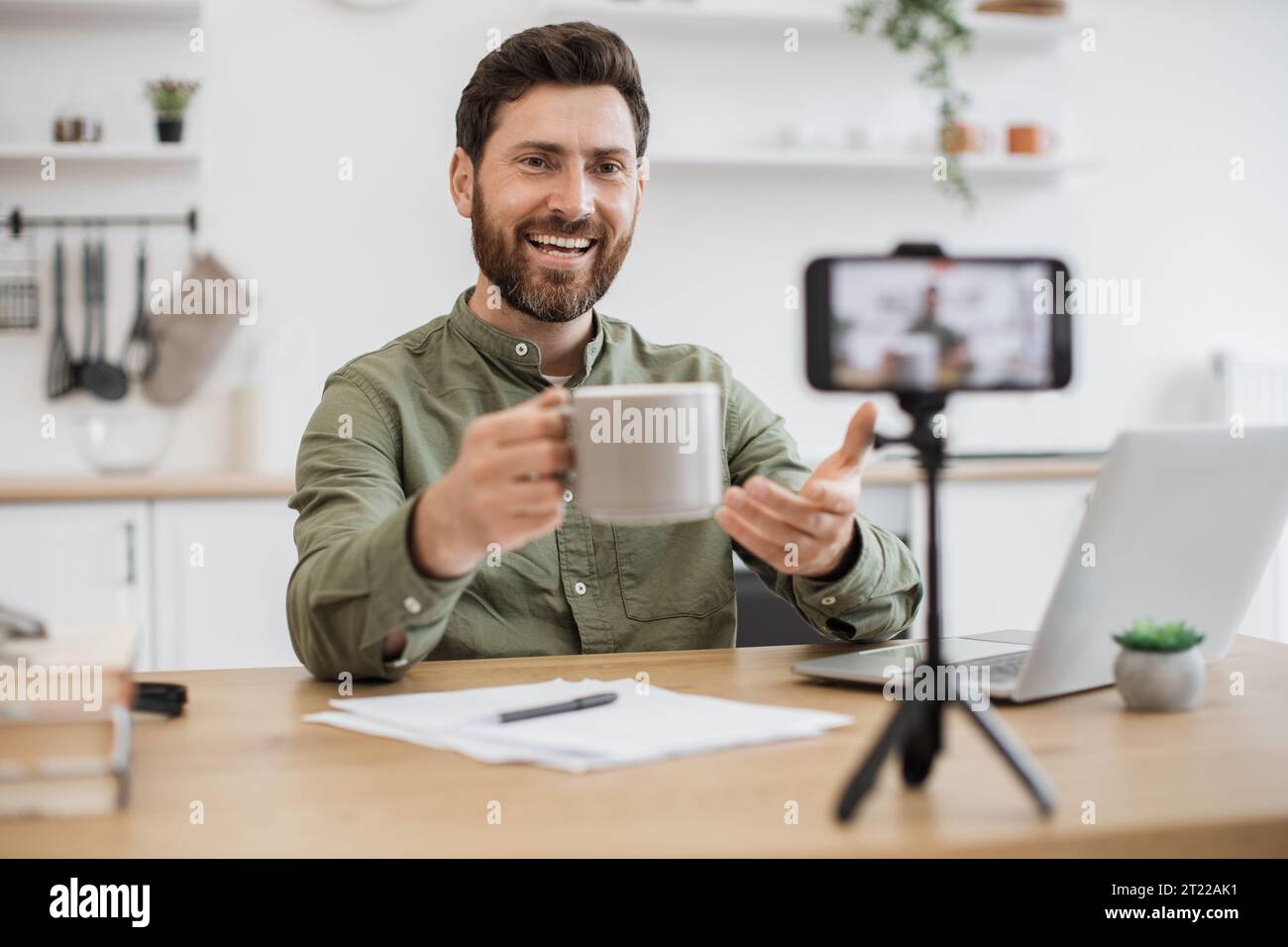 Happy attractive streamer sitting at table near modern laptop and ...