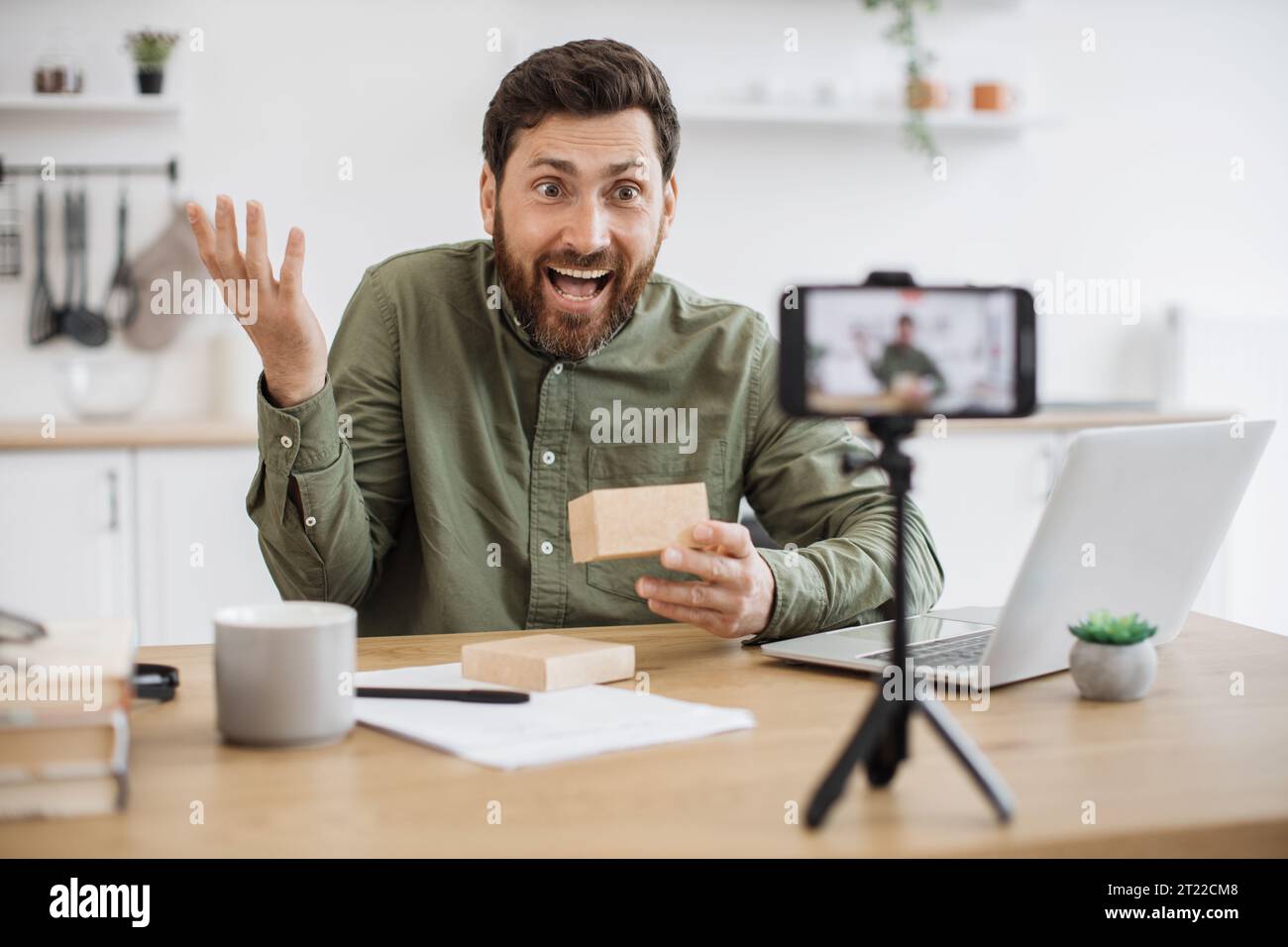 Emotional young guy opening cardboard box and looking inside with ...