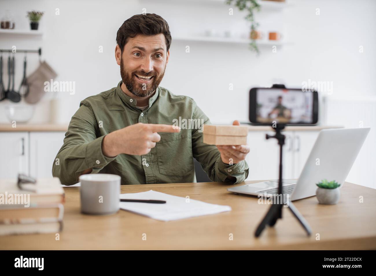Emotional young guy opening cardboard box and looking inside with ...