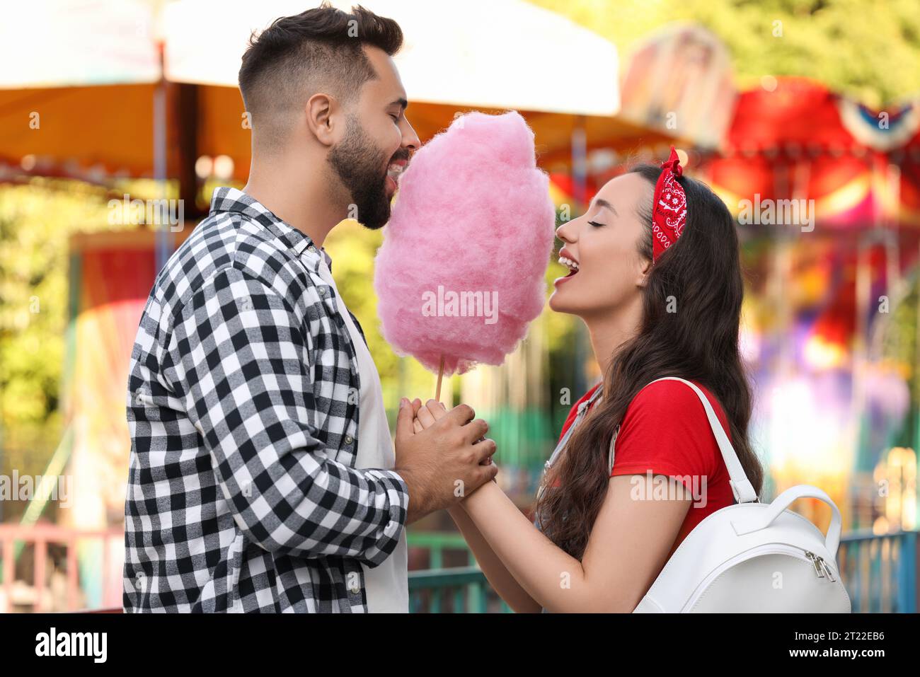Happy couple eating cotton candy at funfair Stock Photo - Alamy
