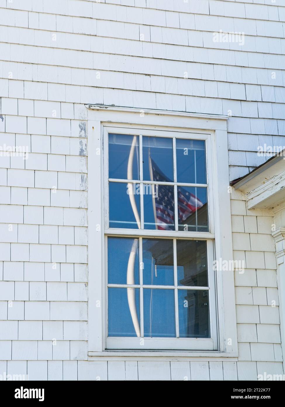 Distorted reflection of American flag and pole in window panes of ...