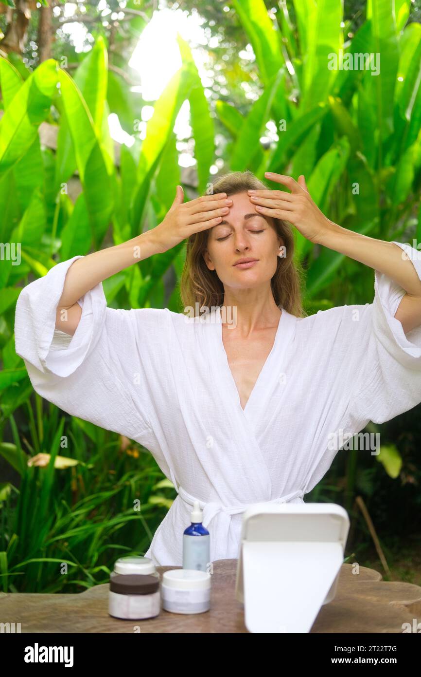 Vertical portrait of a middle aged woman doing a facial and neck ...