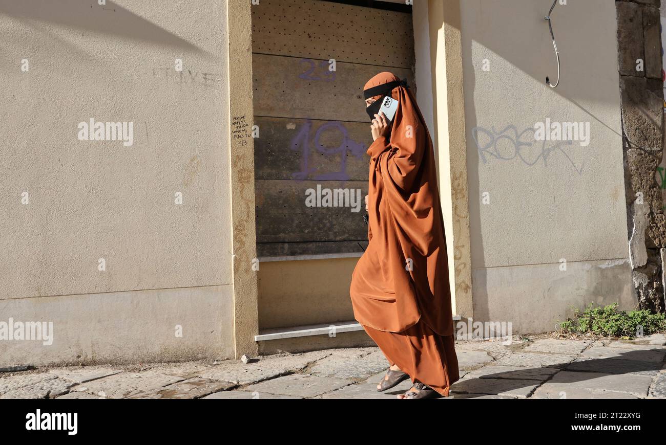 A Muslim women uses her smartphone as she walks through the old town of ...