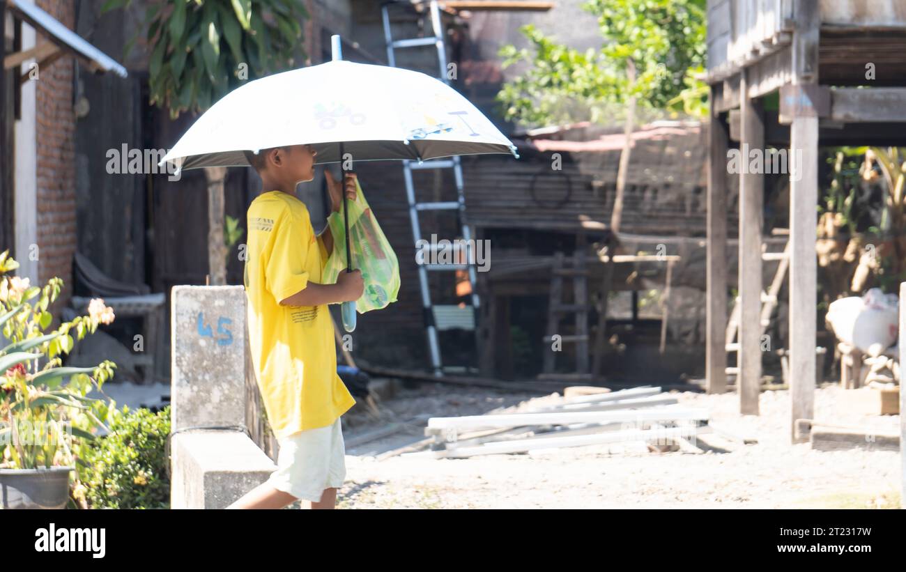 Pinrang Indonesia, October 16, 2023: A boy walks using an umbrella ...