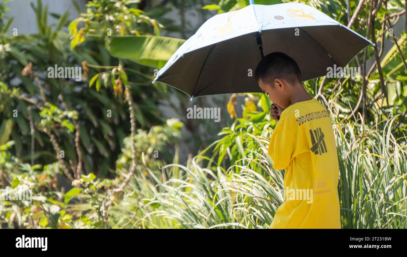 Pinrang Indonesia, October 16, 2023: A boy walks using an umbrella ...