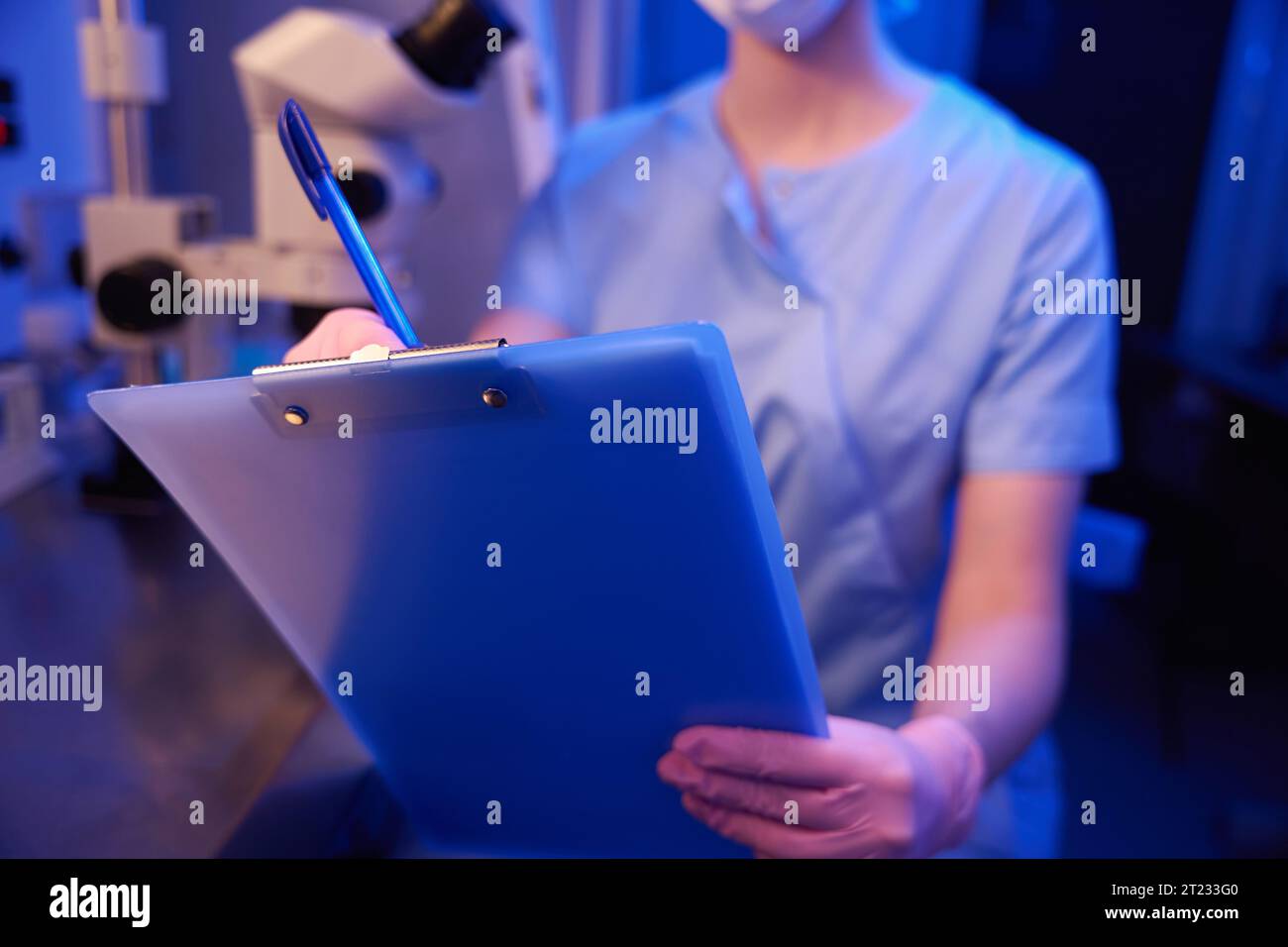 Lab researcher recording results after microscopic examination of cell ...