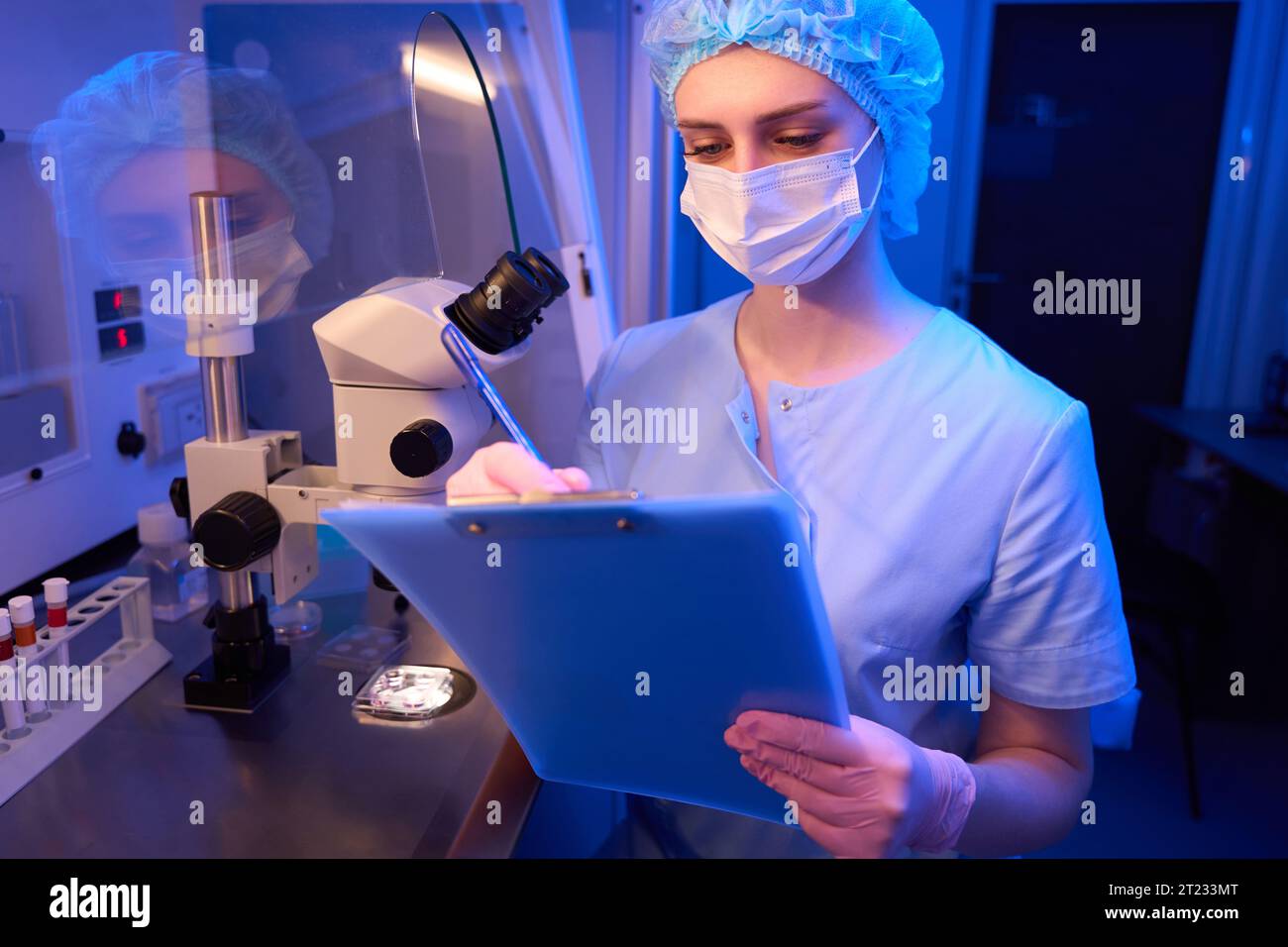 Researcher recording results after microscopic examination of ...