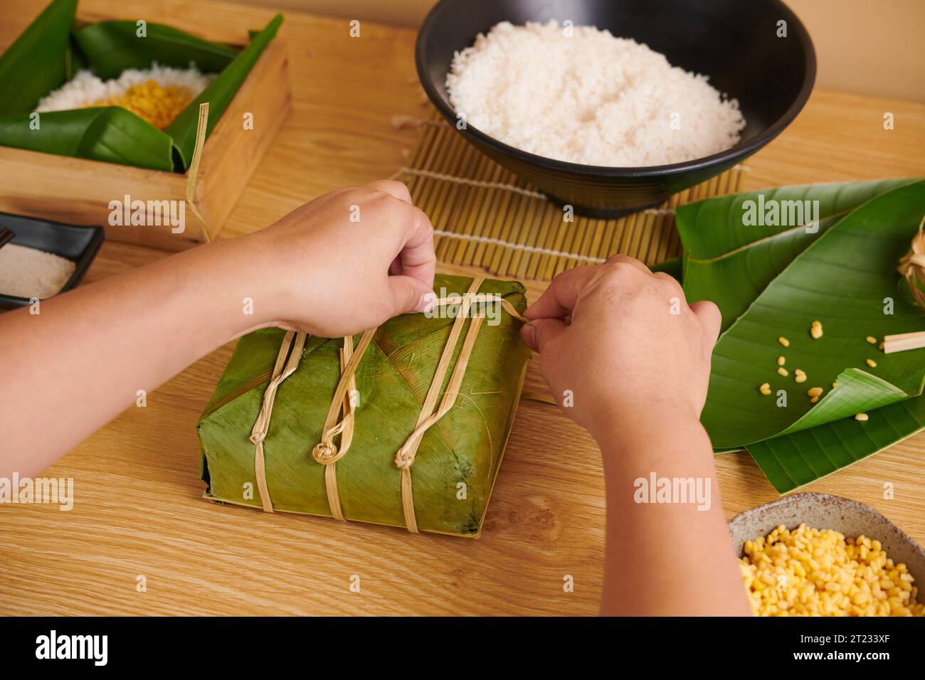 Hands tying wrapped Vietnamese square cake with bamboo strings Stock ...