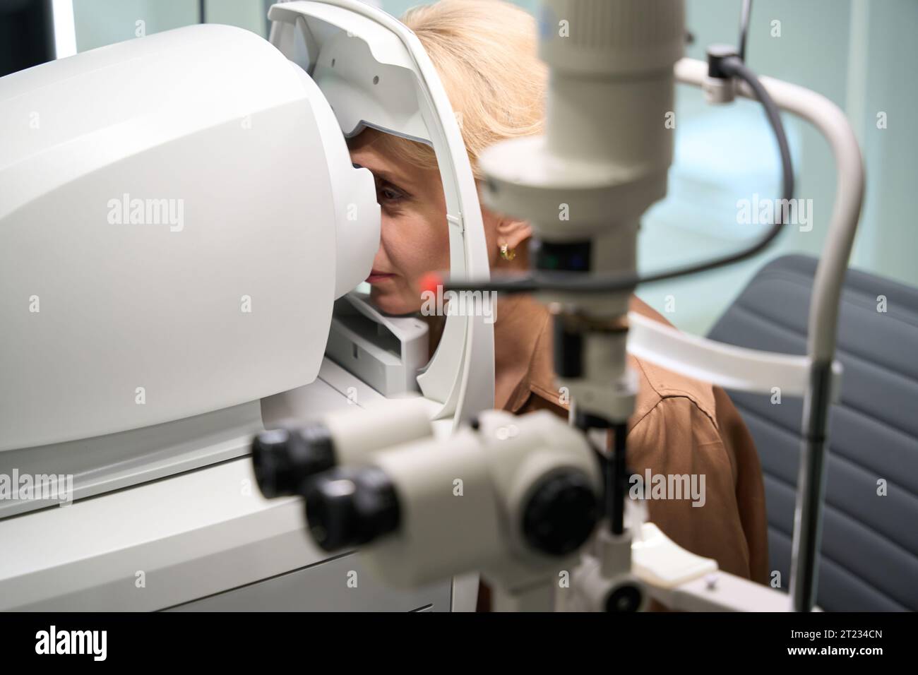 Elegant woman sits in front of a special ophthalmic device Stock Photo ...