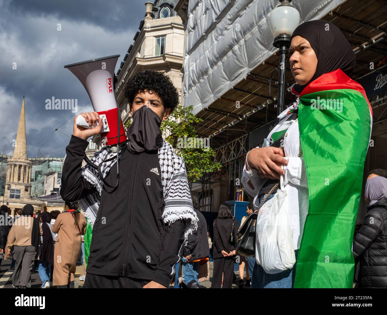 London, UK. 14 Oct 2023: A masked teenage boy holds a megaphone as he ...