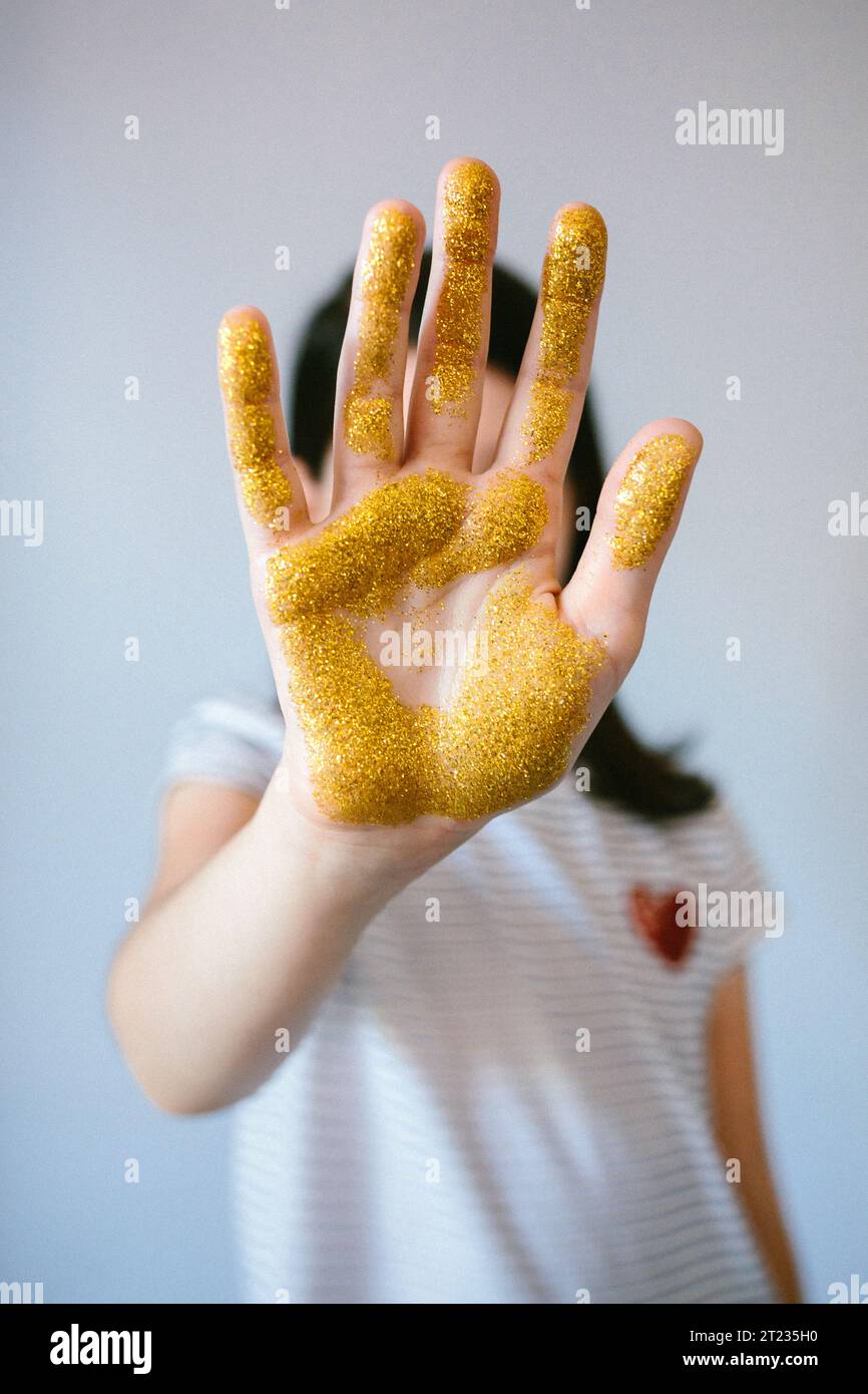 Unrecognizable young girl showing her palm hand covered of golden ...