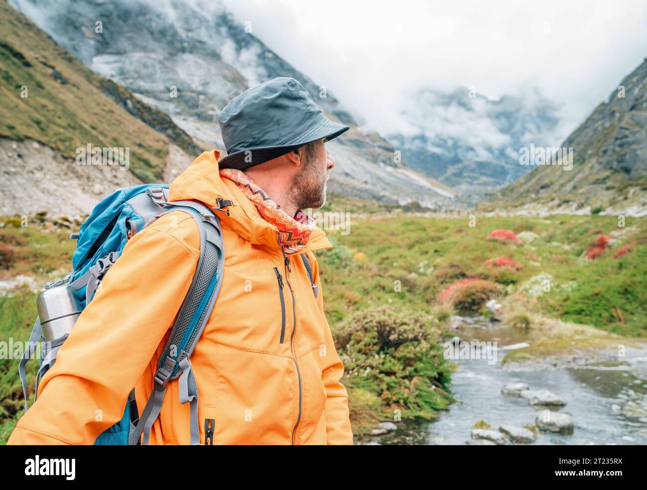 Man with backpack dressed orange waterproof jacket turning back ...