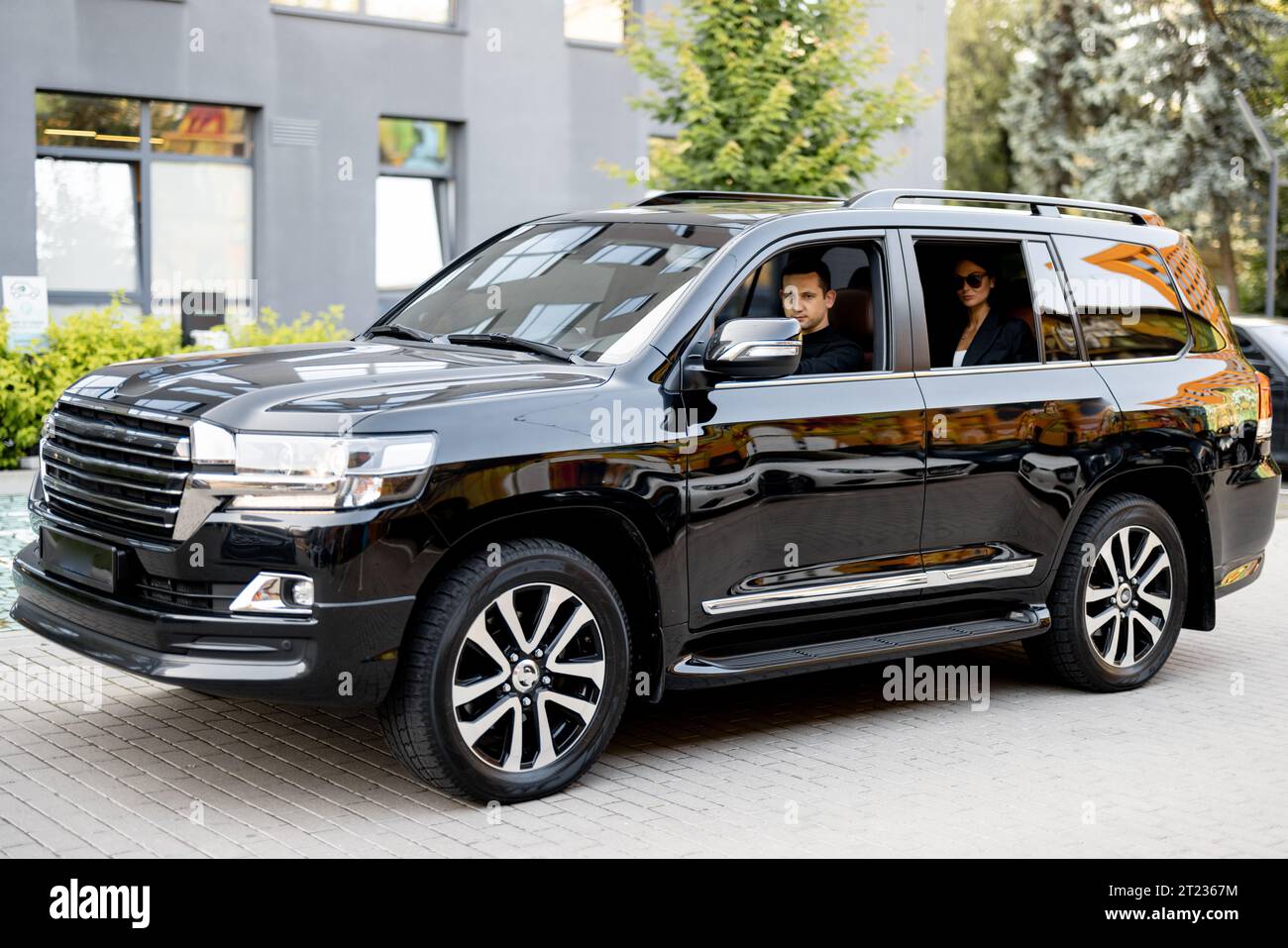 Side view of a luxury SUV vehicle with male driver and business lady ...