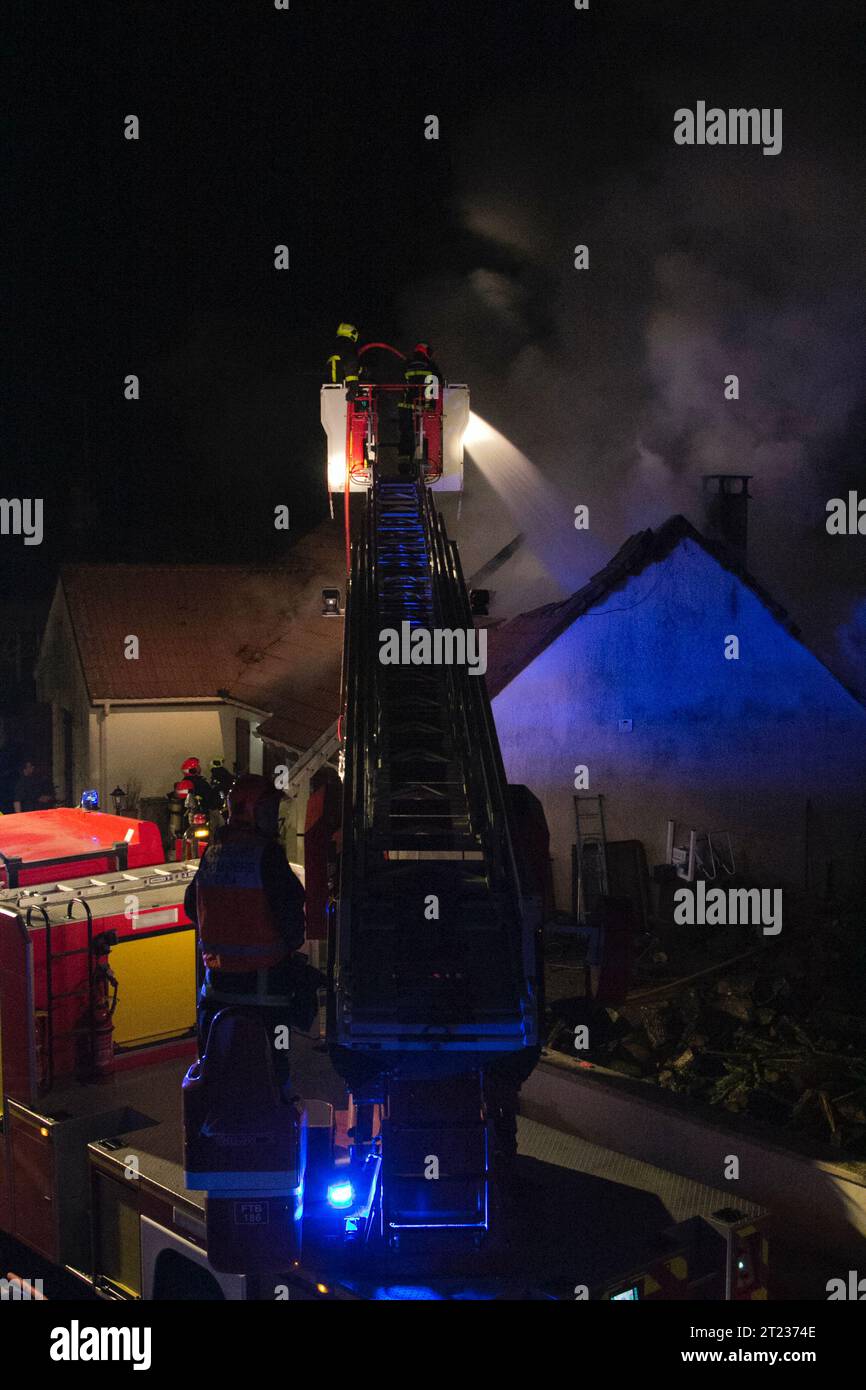 Firemen hose gallons of water onto the roof of a house on fire in a ...