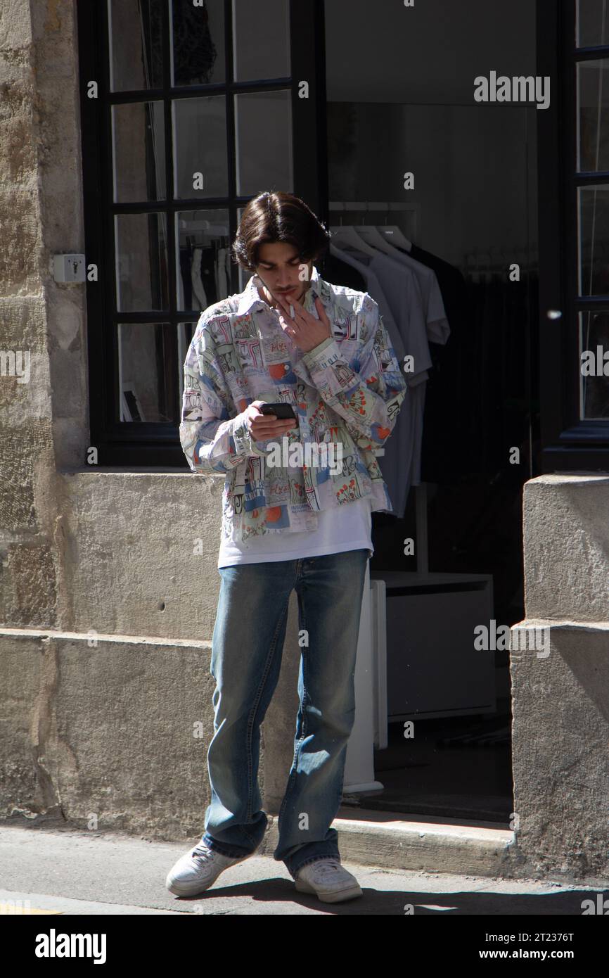A young shopkeeper takes a break outside a shop in Paris, France Stock ...