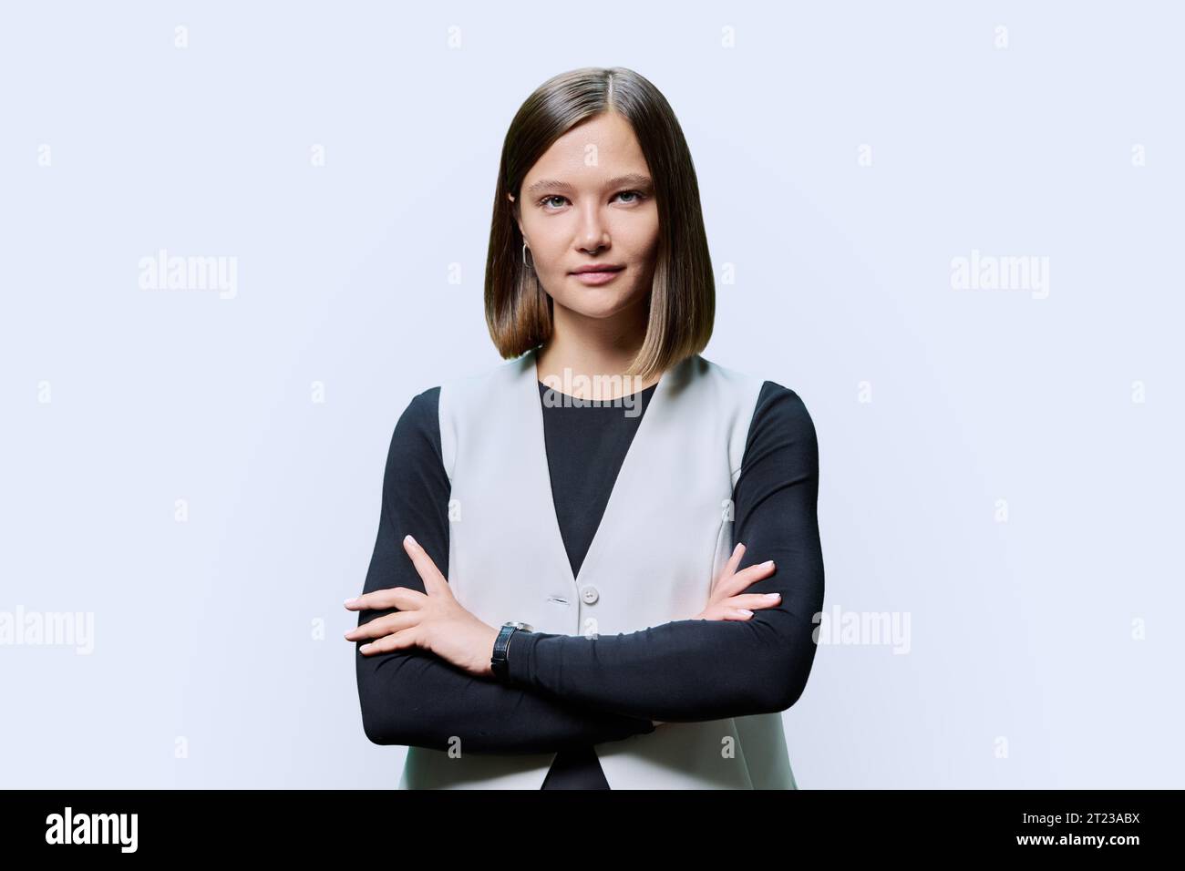Serious confident young woman with crossed arms posing against white ...