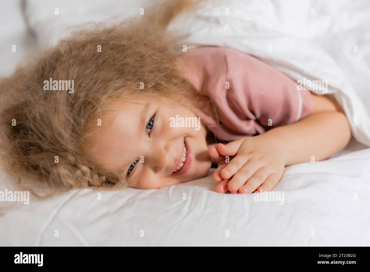 Cute curly-haired girl sleeping in bed covered with a blanket Stock ...