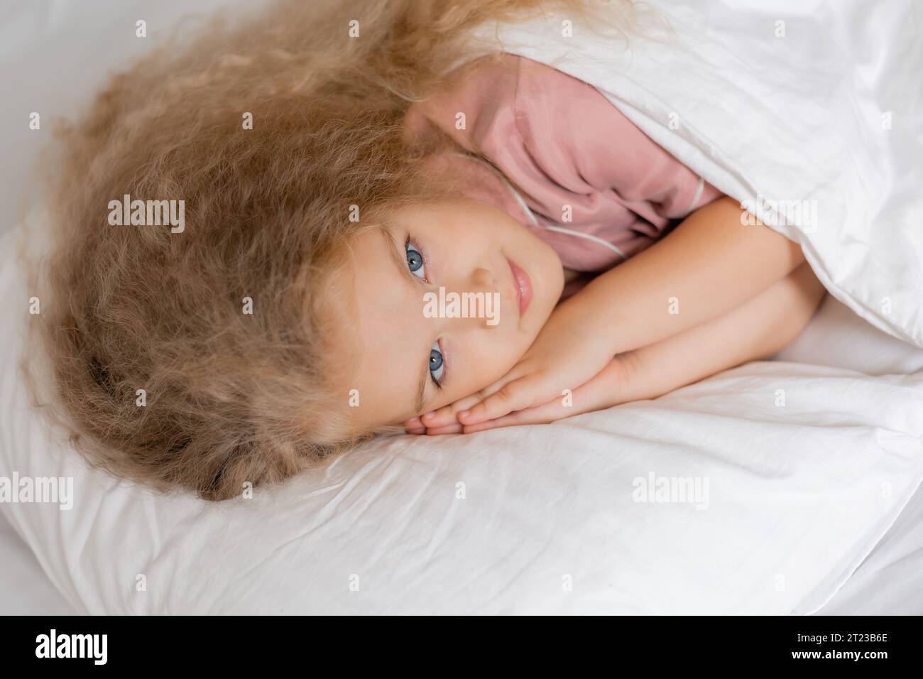 Cute curly-haired girl sleeping in bed covered with a blanket Stock ...