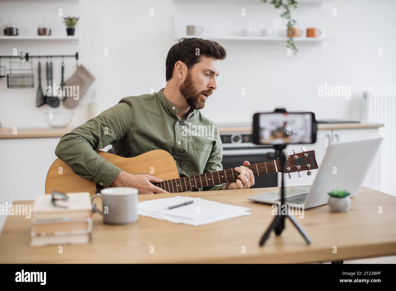 Inspired man playing guitar while recording video on mobile Stock Photo ...