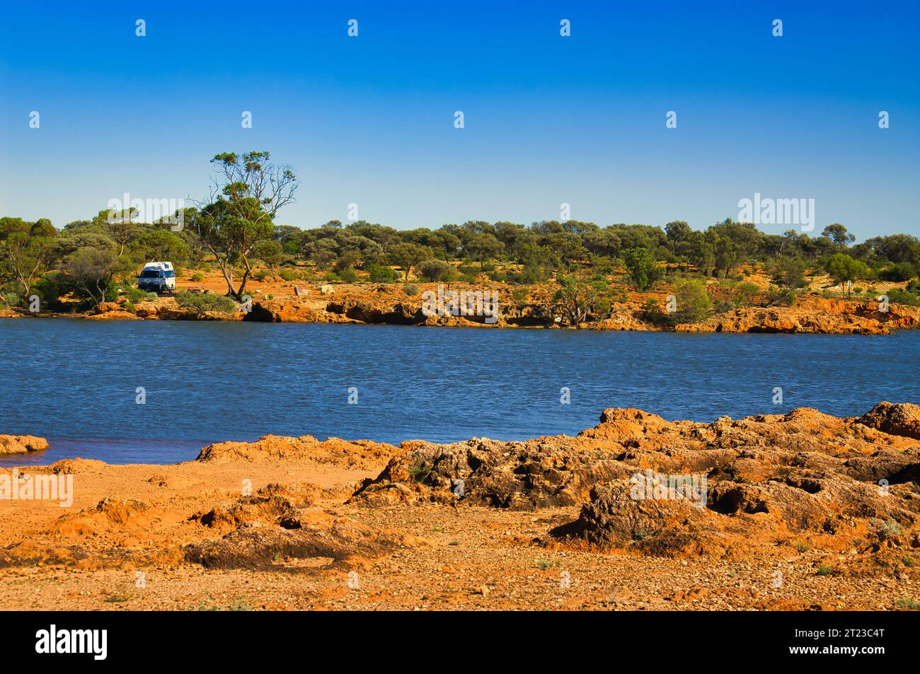 Water in the dry, red Australian outback, small camper parked on the ...