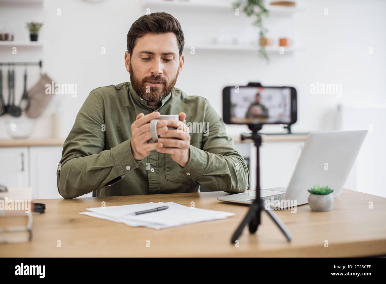 Unwell man vlogger filming blog and drinking tea from mug Stock Photo ...