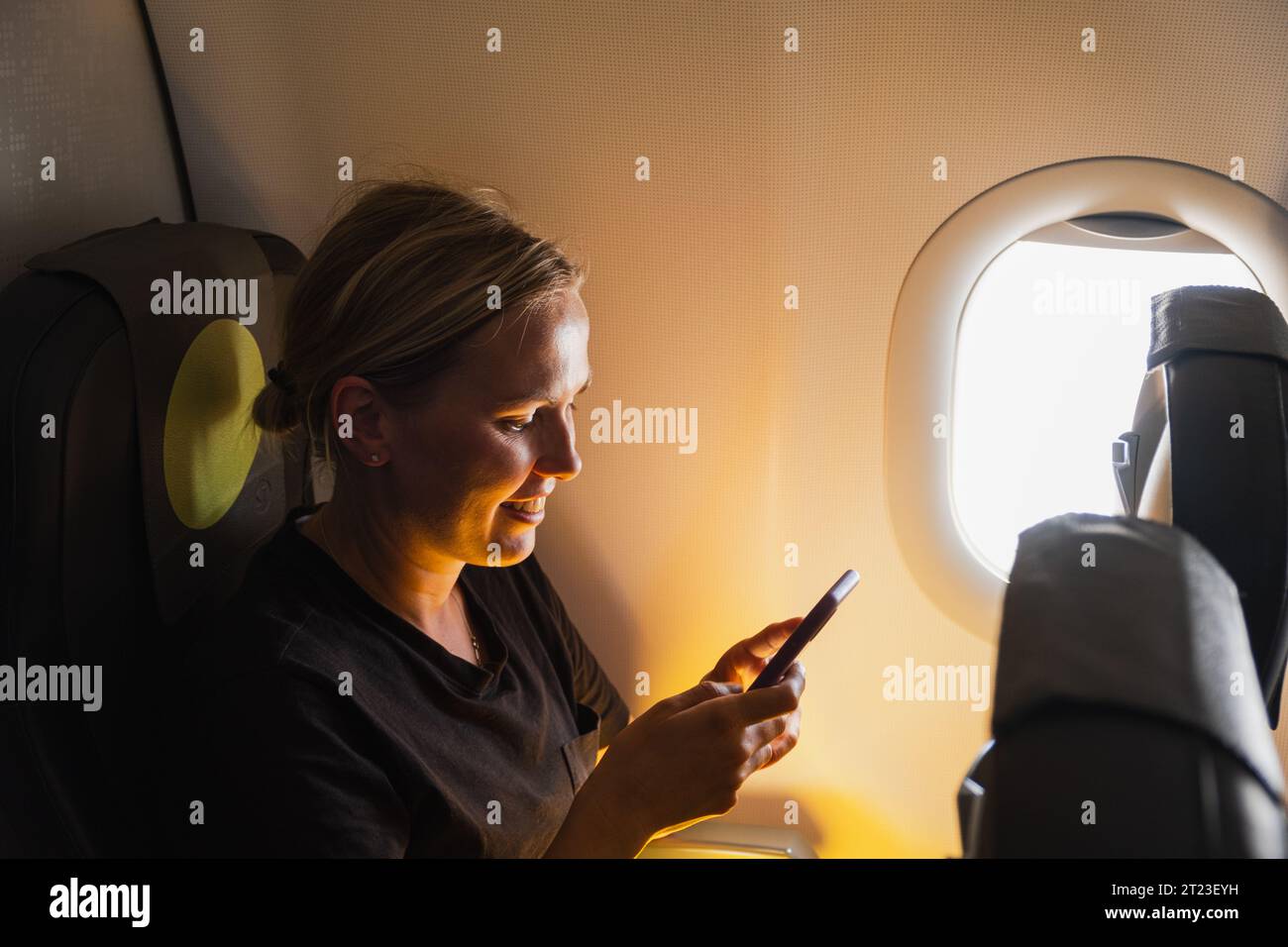 Passenger woman is flying in plane. Girl using phone sitting by ...
