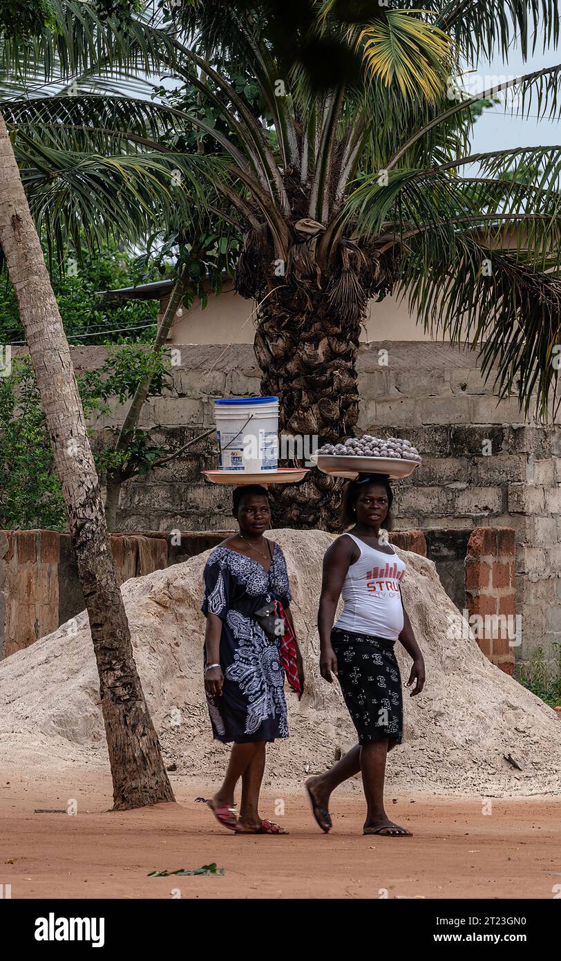 Lome, Togo -- May 14, 2023. Two women walk through a Togo village while ...